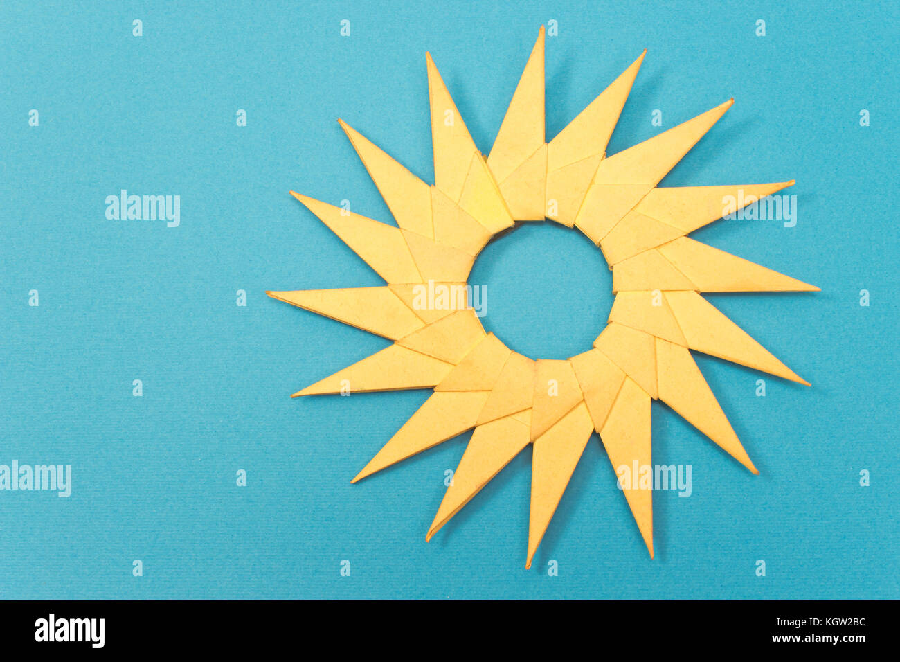 Origami yellow paper sun isolated on blue background Stock Photo - Alamy