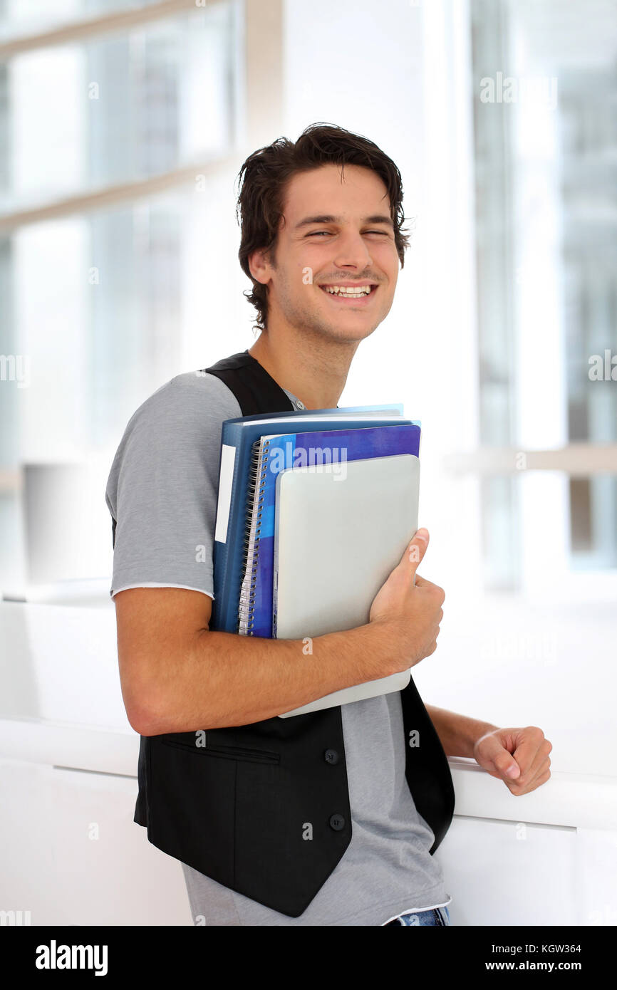 Cheerful college student standing in hall Stock Photo - Alamy