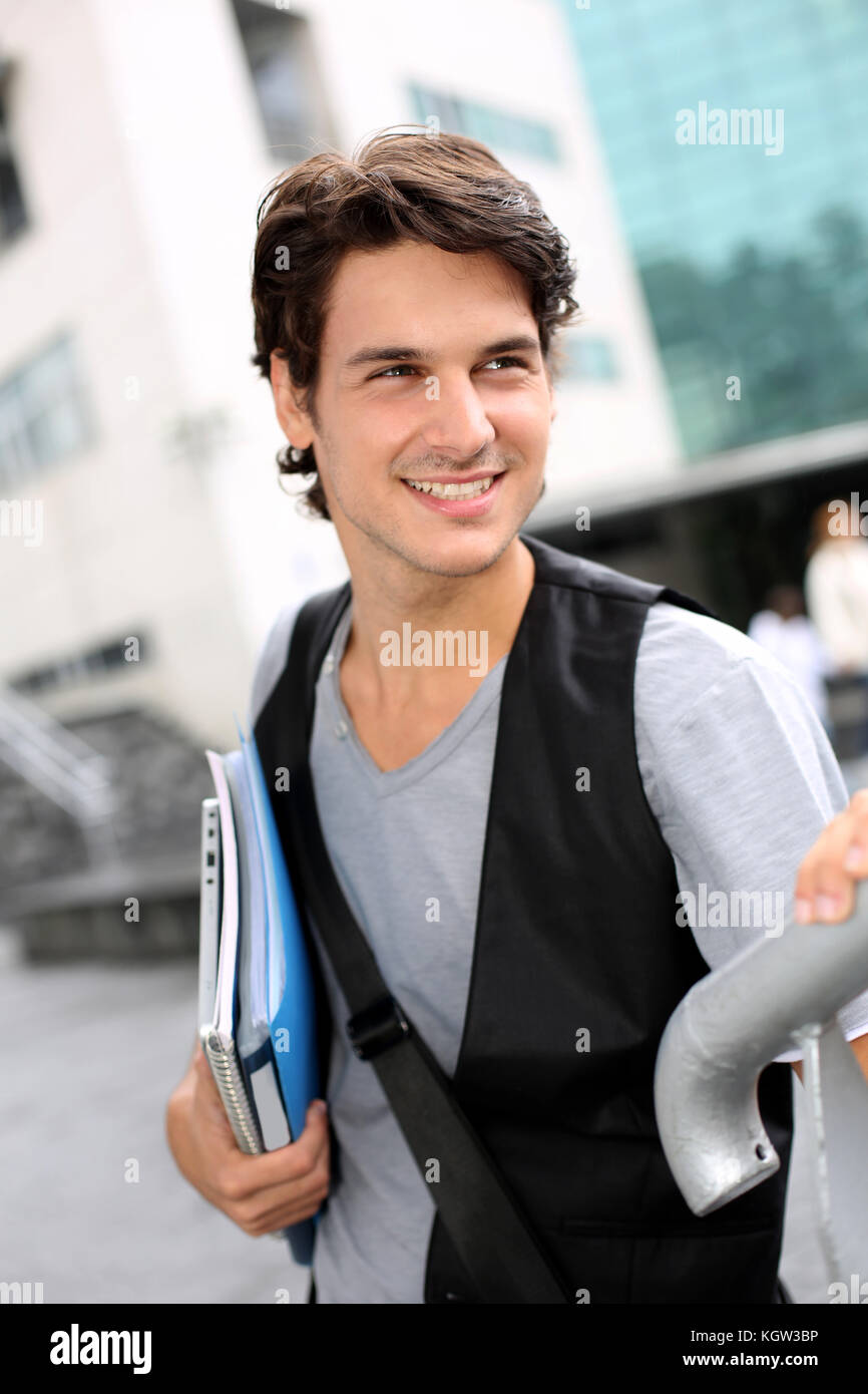 Cheerful student standing outside college building Stock Photo - Alamy