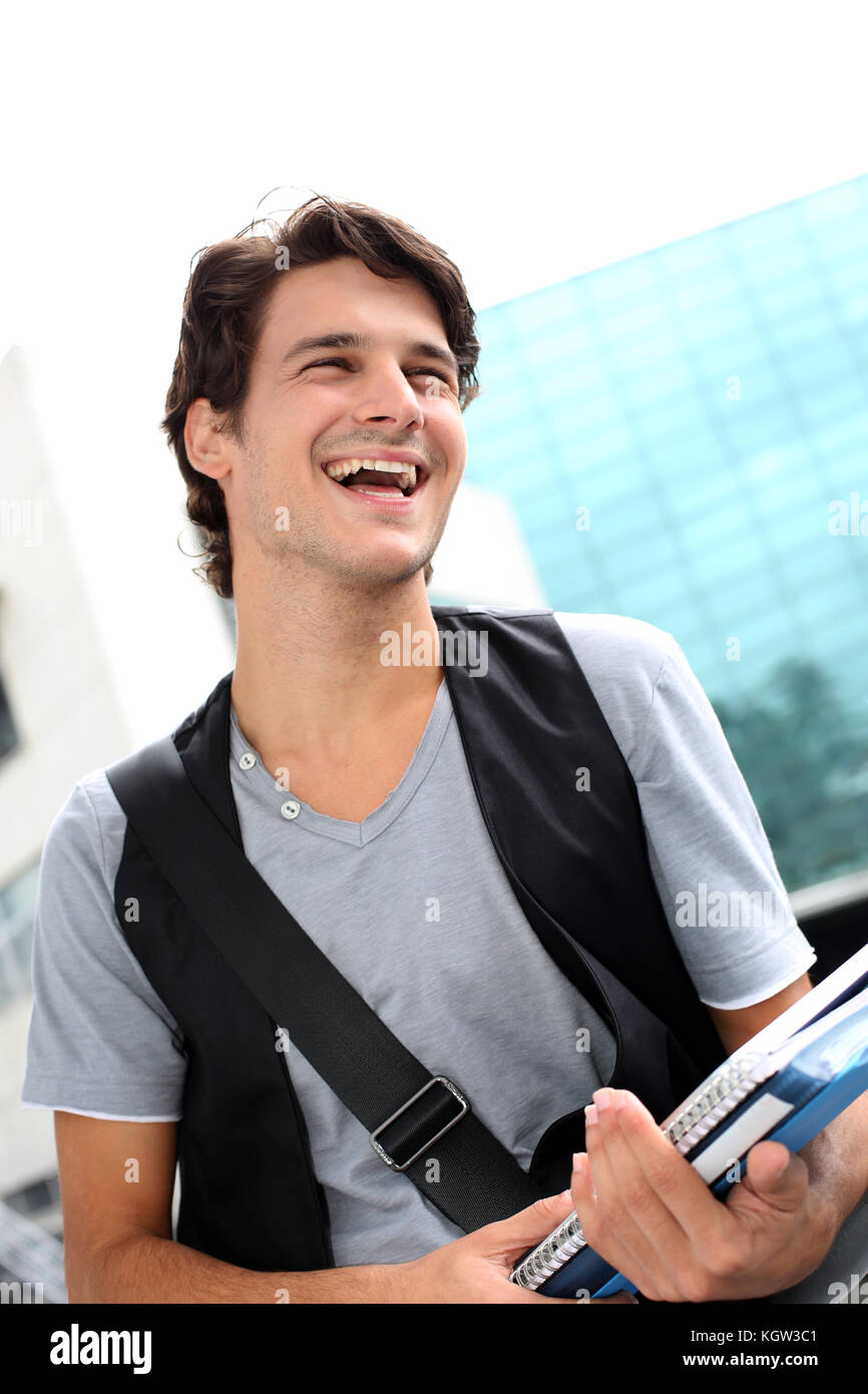 Cheerful student standing outside college building Stock Photo - Alamy