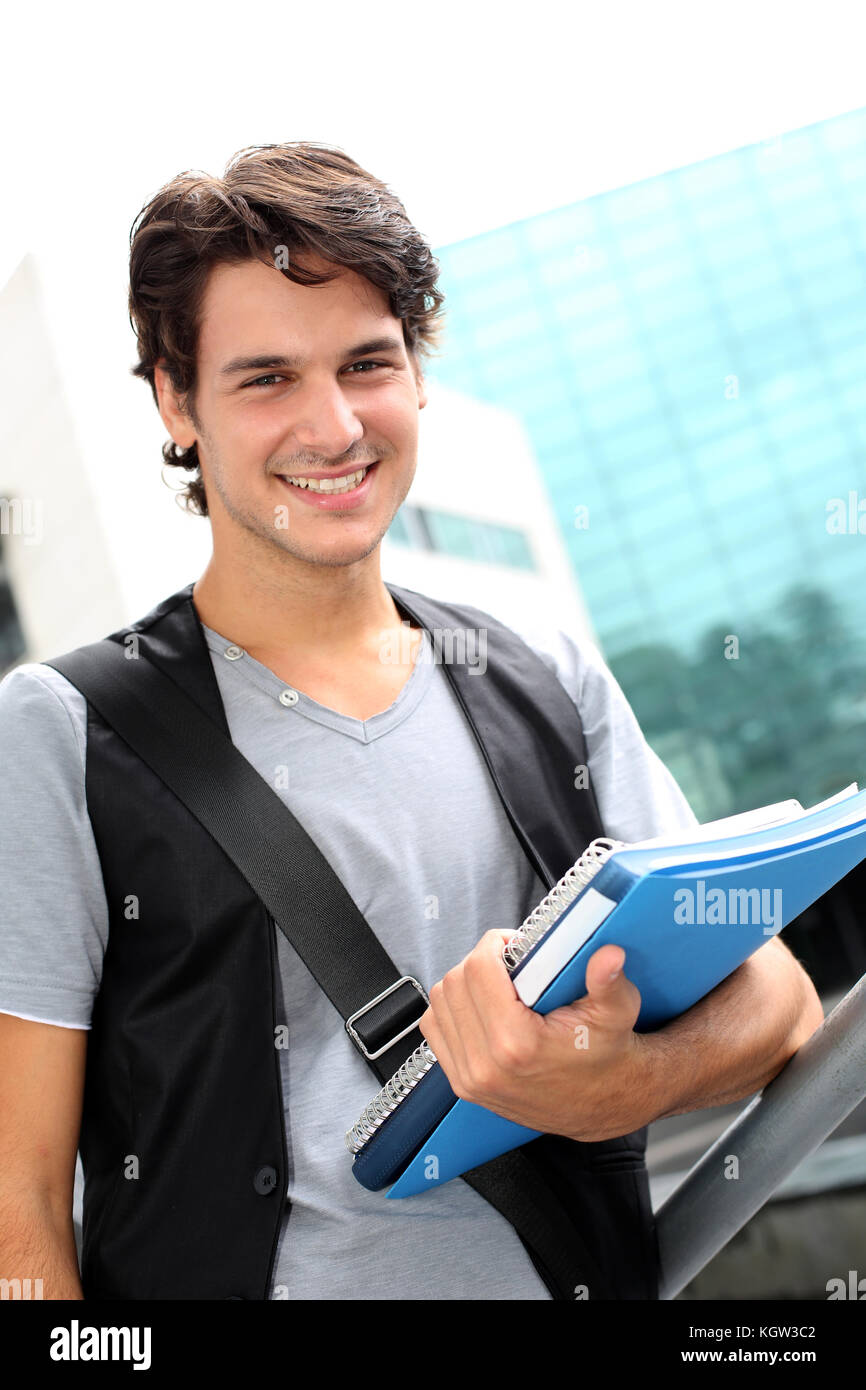 Cheerful student standing outside college building Stock Photo - Alamy
