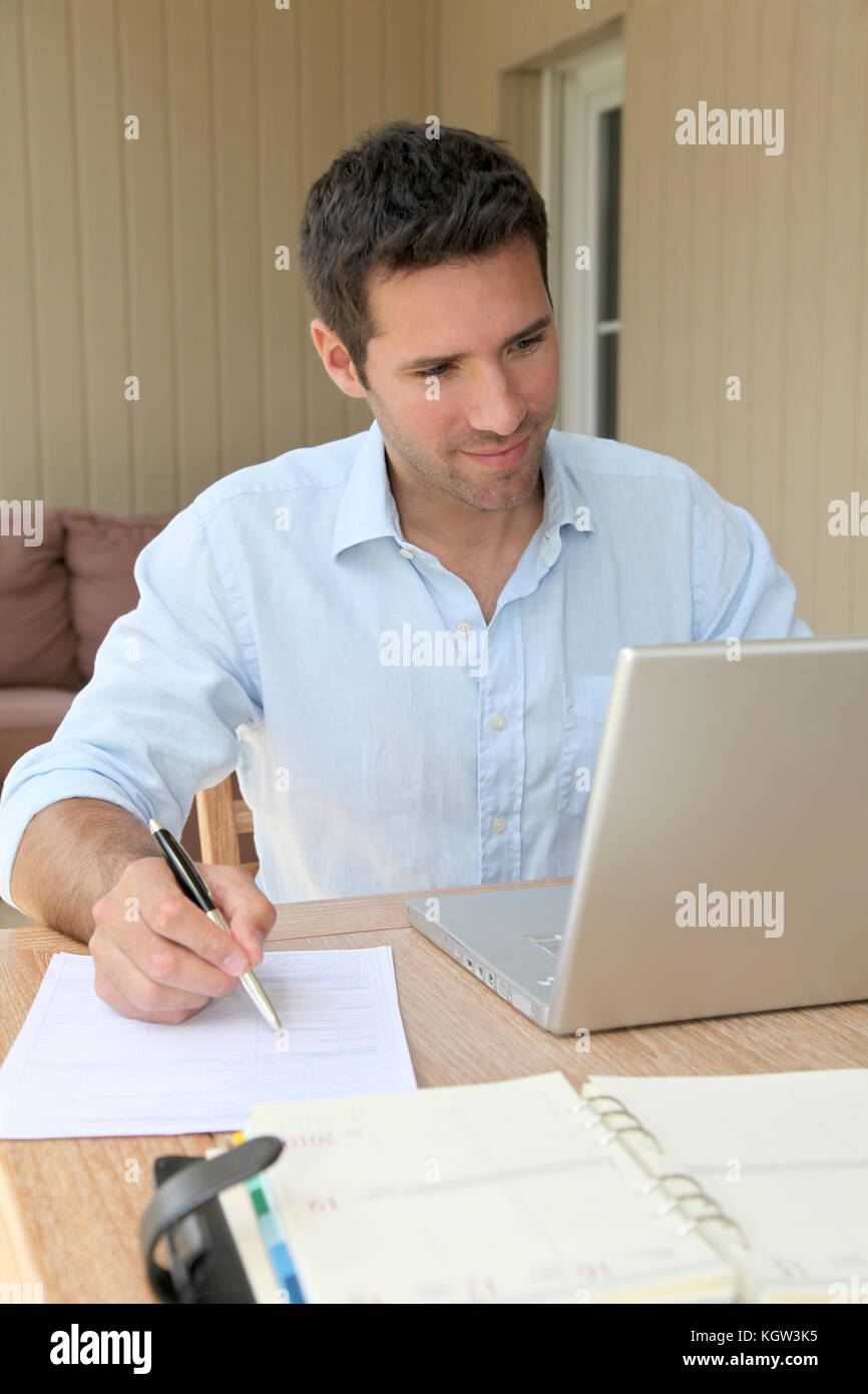 Smiling man working at home on laptop computer Stock Photo - Alamy