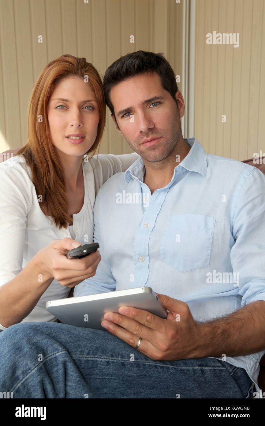 Couple sitting in sofa with tv remote control Stock Photo - Alamy