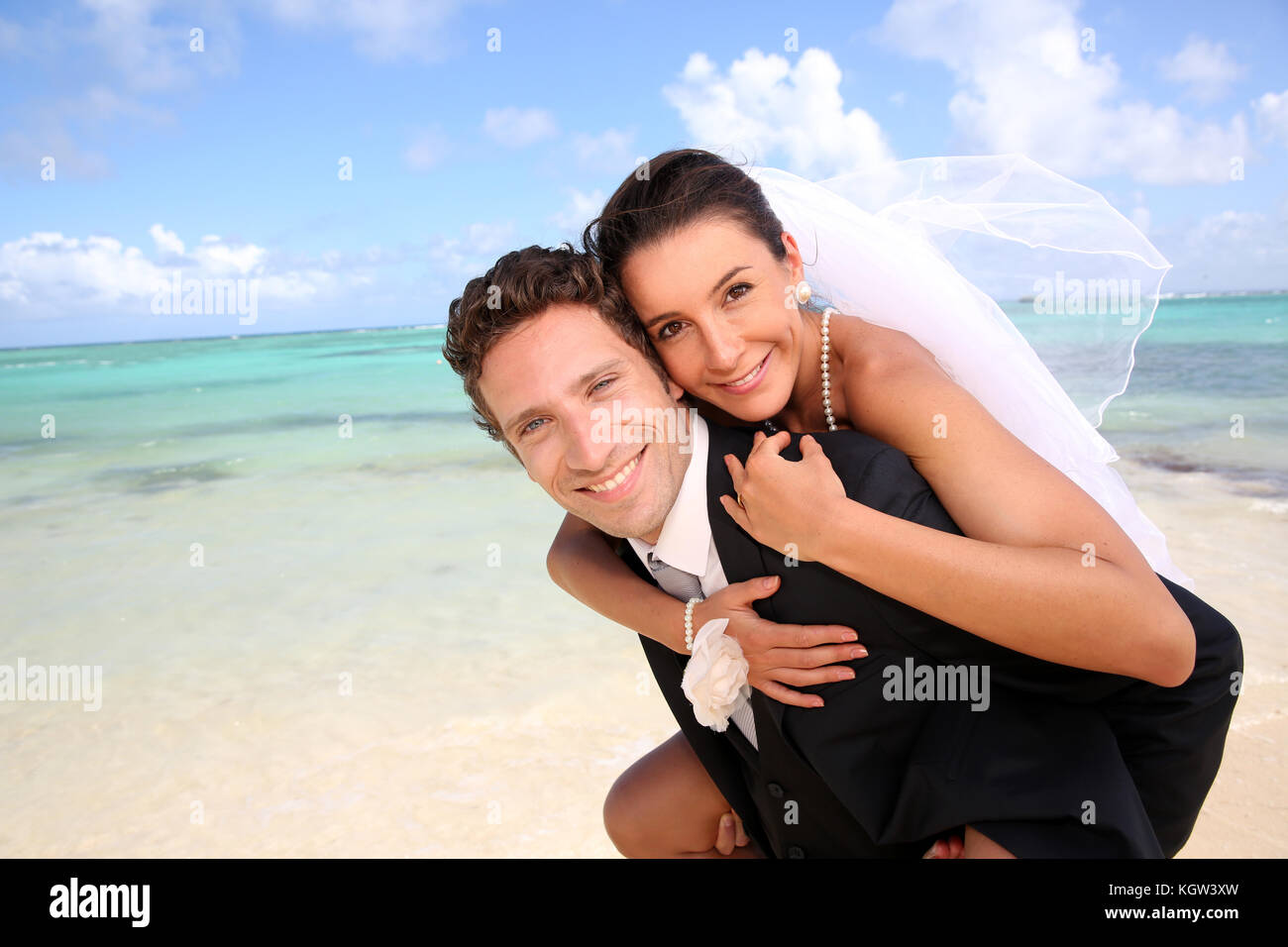 Groom carrying bride on his back at the beach Stock Photo - Alamy