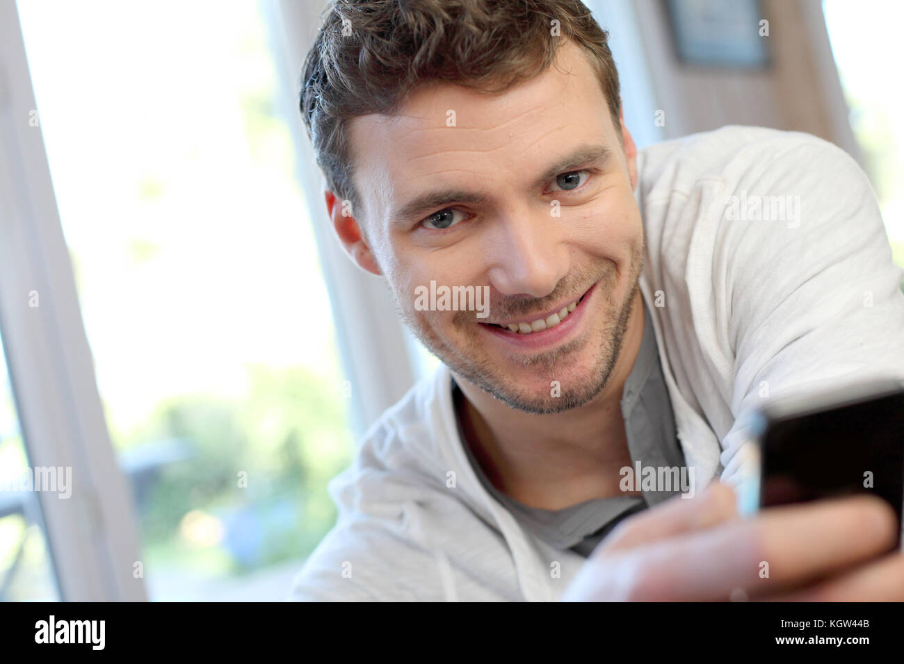 Young man using mobile phone to send short message Stock Photo - Alamy