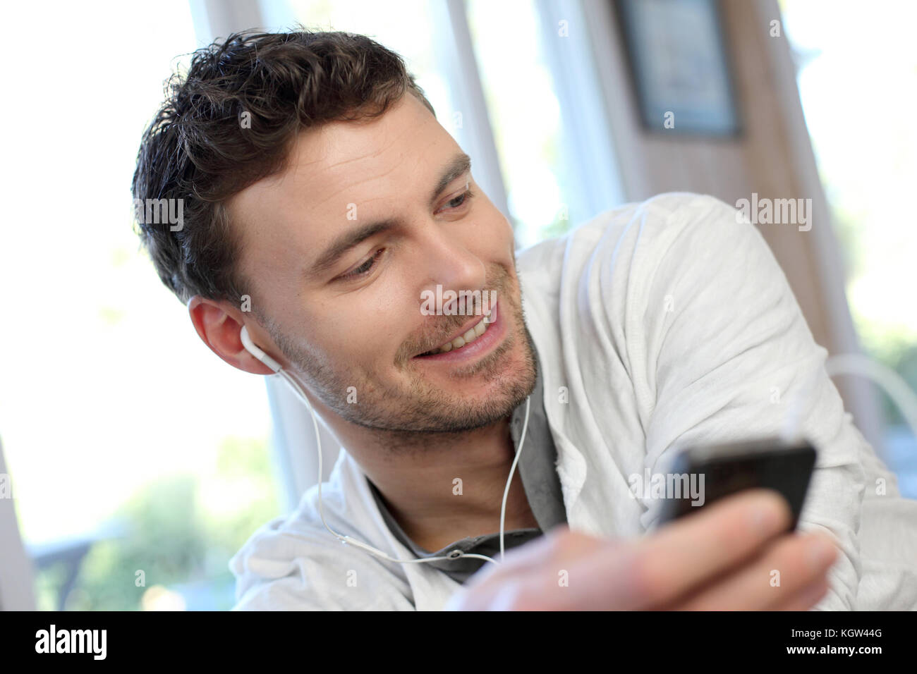 Young man using mobile phone with handsfree headset Stock Photo - Alamy
