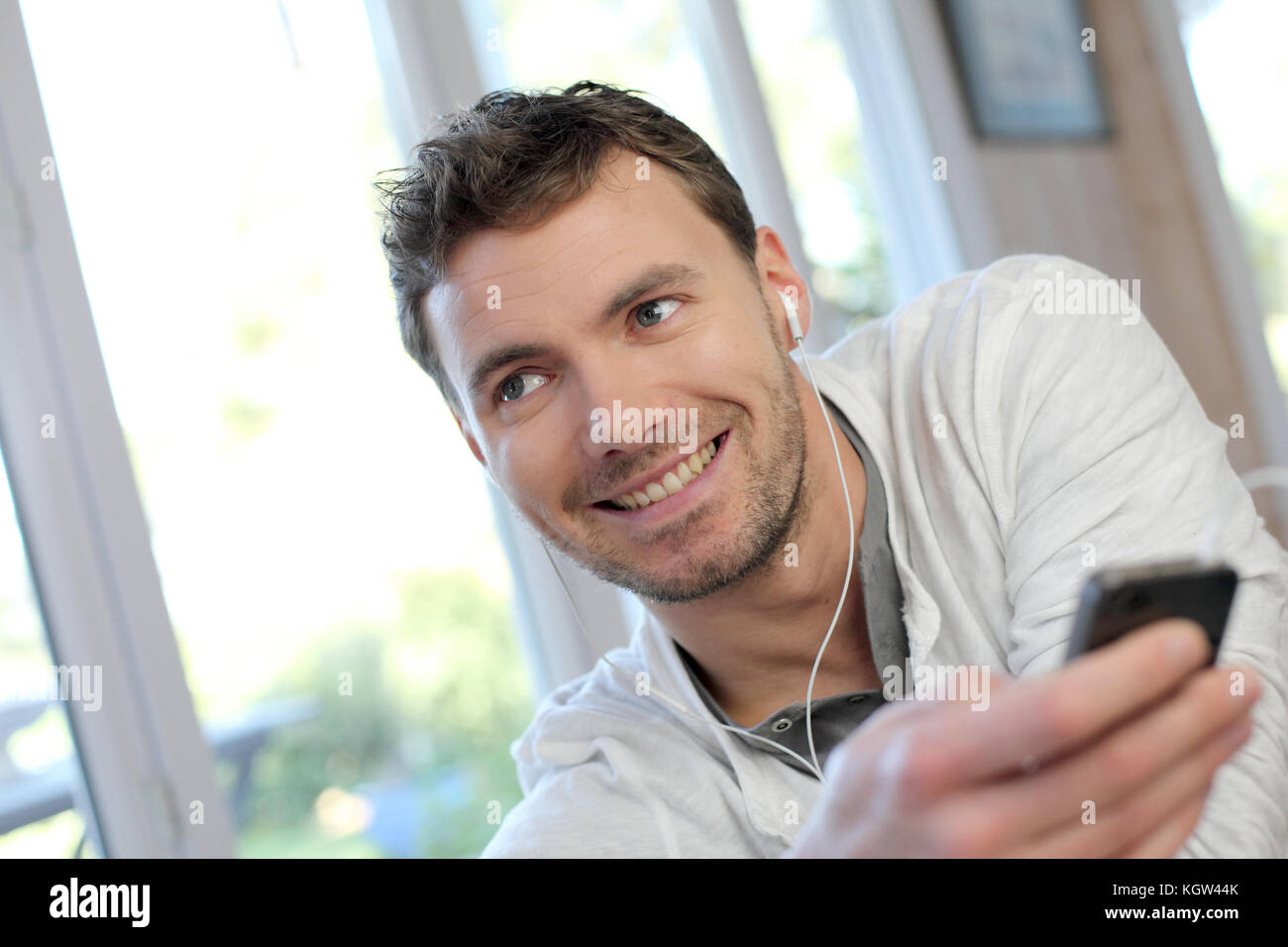 Young man using mobile phone with handsfree headset Stock Photo - Alamy