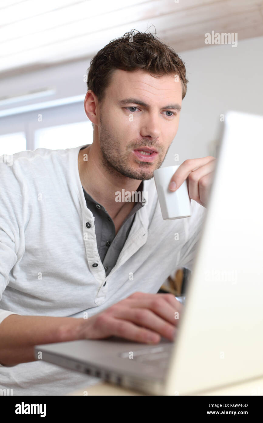 Man drinking coffee in front of laptop computer Stock Photo - Alamy