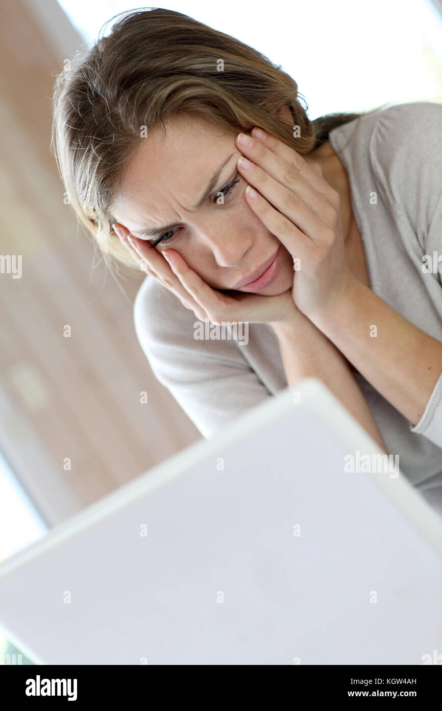 Active woman in front of laptop with upset look Stock Photo - Alamy
