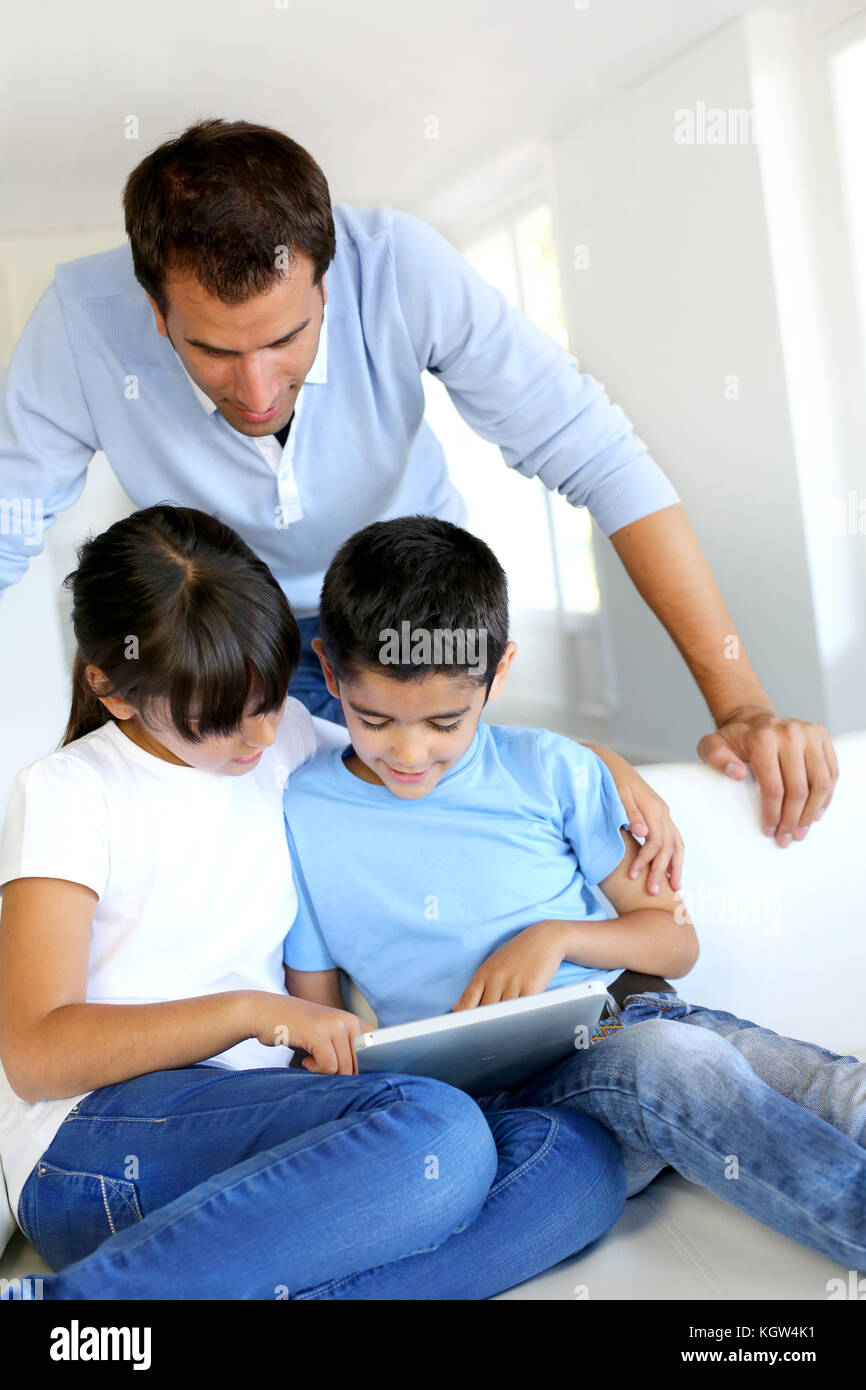 Father controlling children while playing on tablet Stock Photo - Alamy