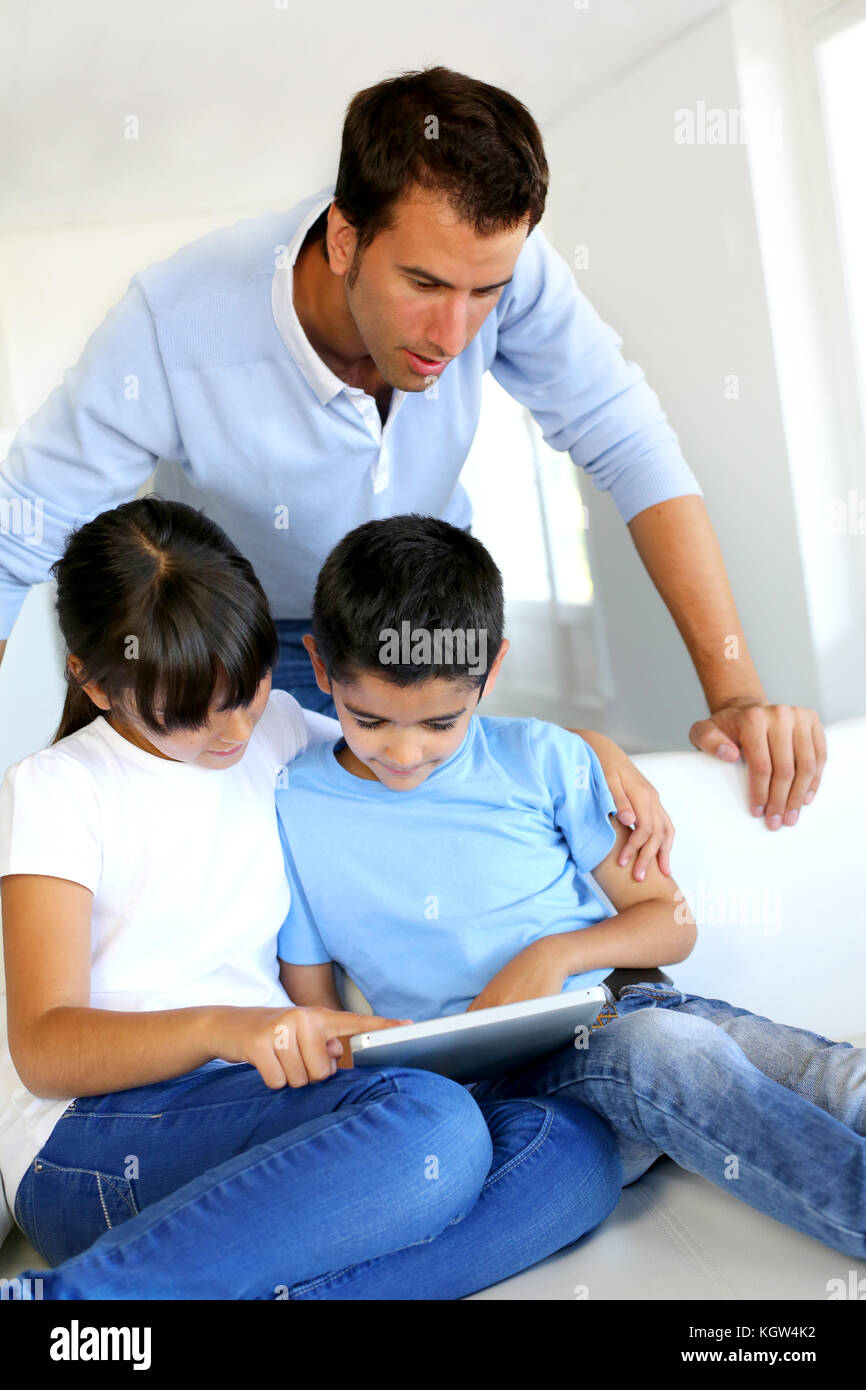 Father controlling children while playing on tablet Stock Photo - Alamy