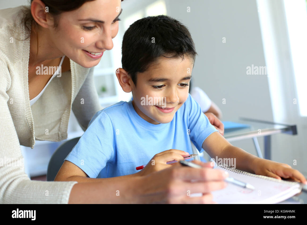Teacher helping young boy with writing lesson Stock Photo - Alamy