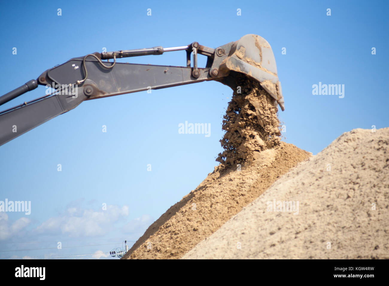A large iron excavator bucket collects and pours sand rubble and stones ...