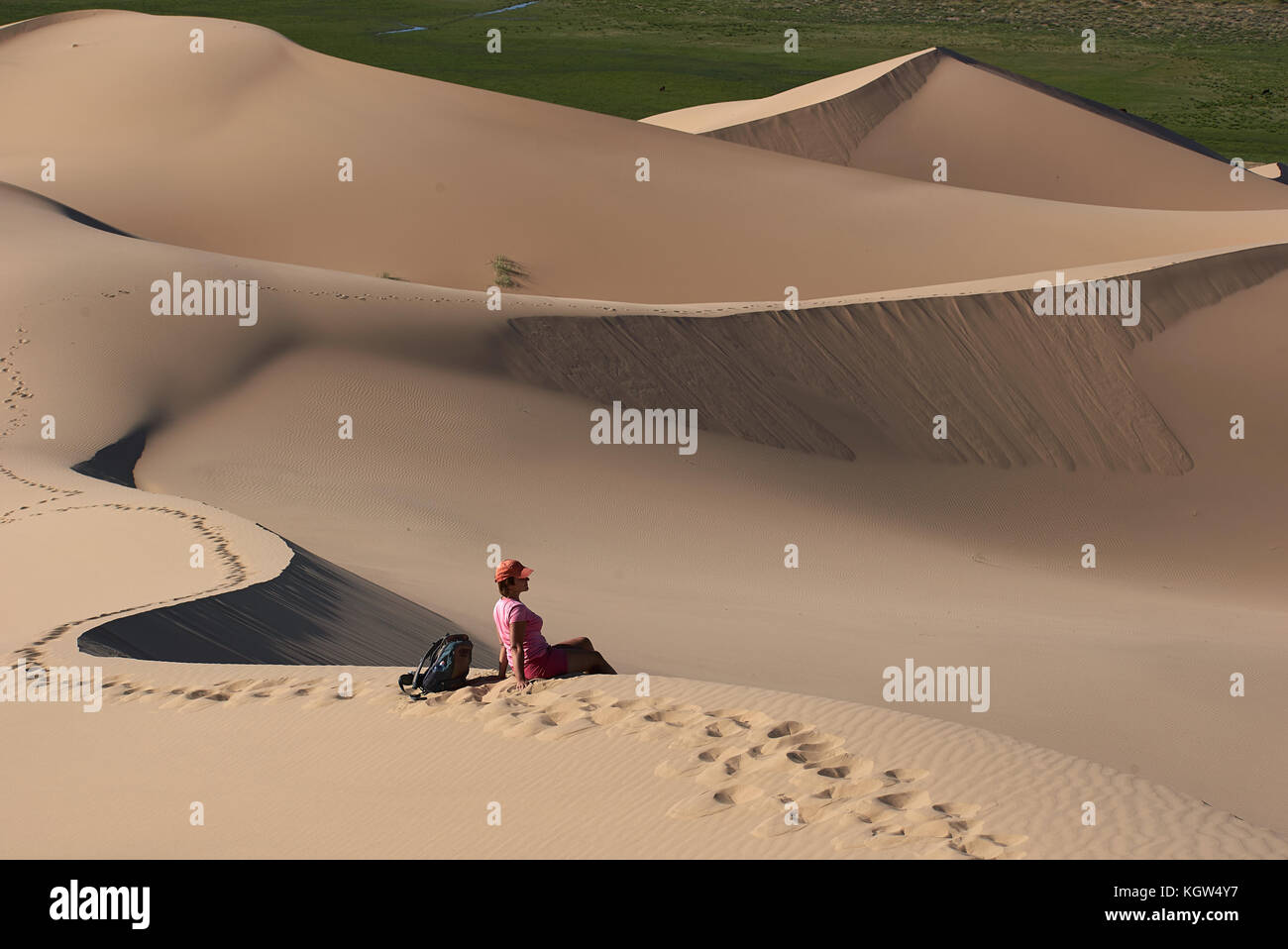 Relaxed tourist sitting on sand dunes in desert and looking at the view ...