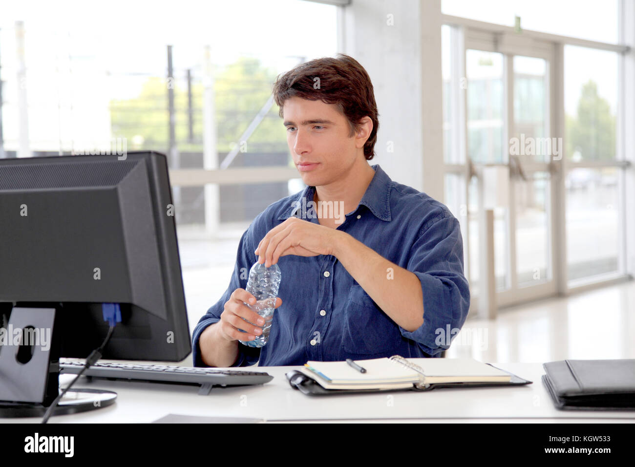 Office worker drinking water in front of desktop computer Stock Photo ...