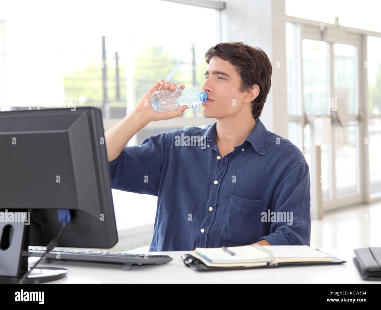 Office worker drinking water in front of desktop computer Stock Photo ...