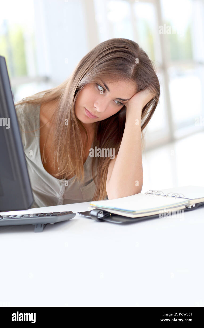 Exhausted young woman sitting in front of computer Stock Photo - Alamy