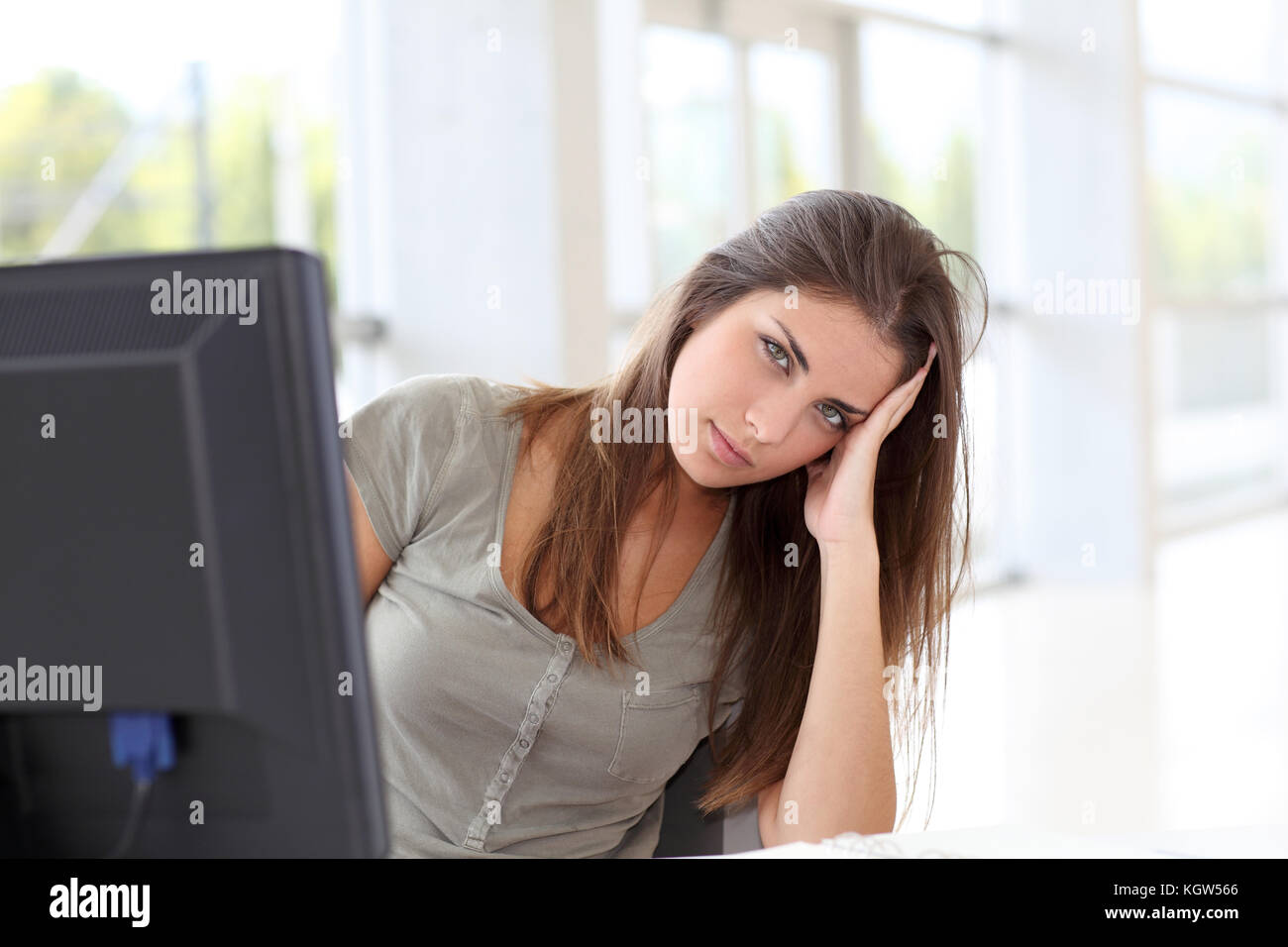 Exhausted young woman sitting in front of computer Stock Photo - Alamy