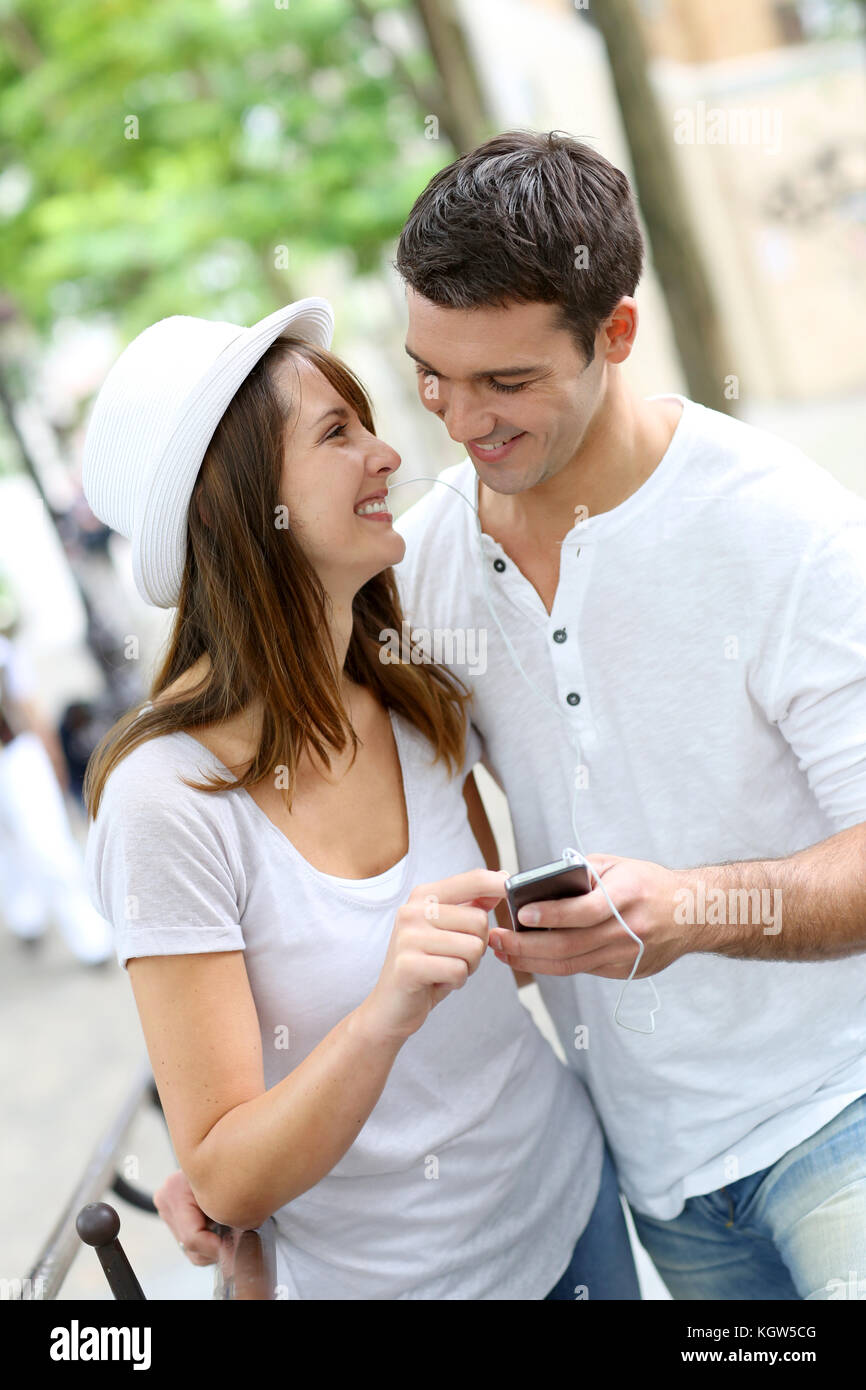 Couple in town using smartphone and handsfree device Stock Photo - Alamy
