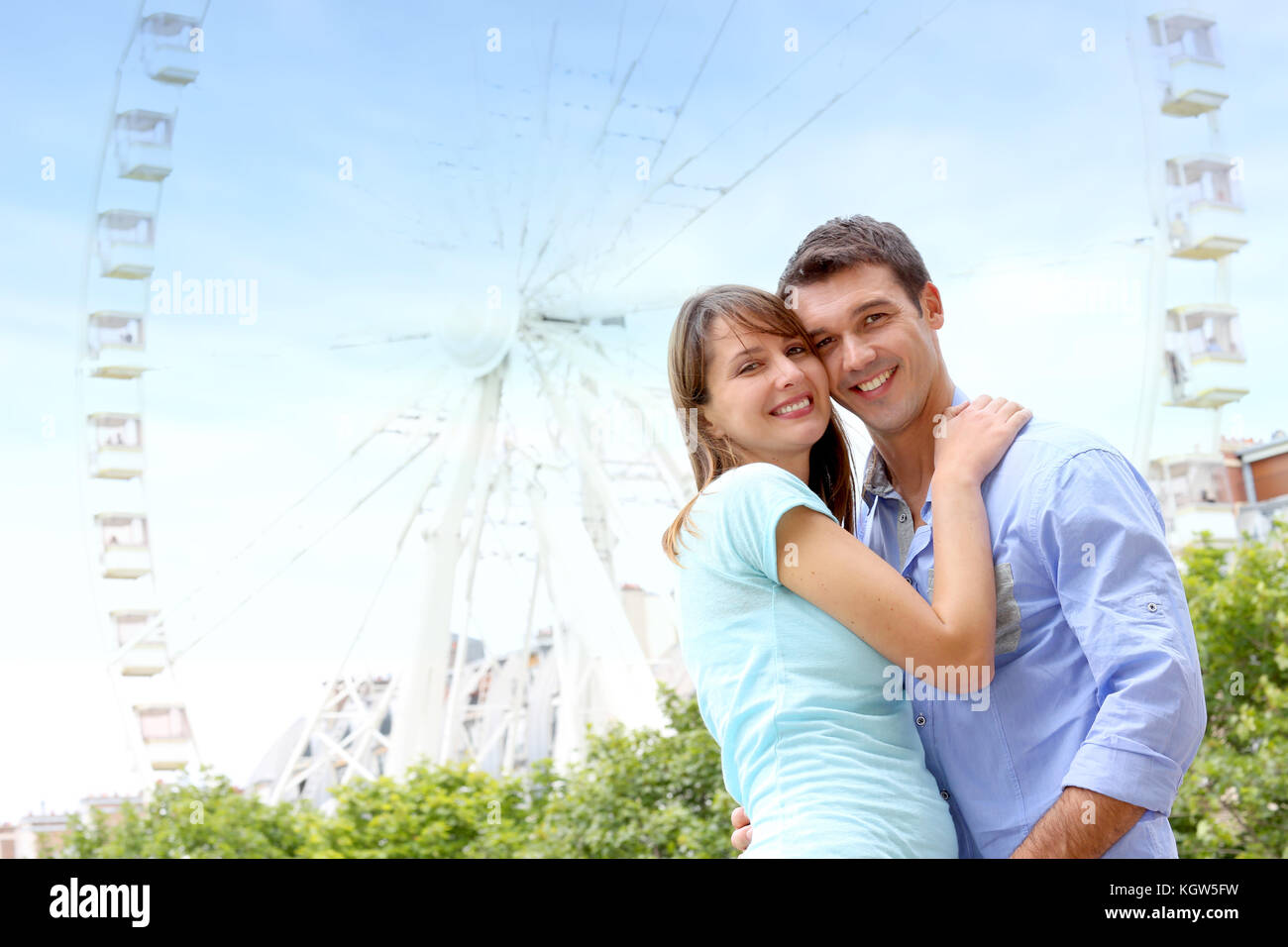 Romantic couple embracing in front of the Ferris Wheel Stock Photo - Alamy
