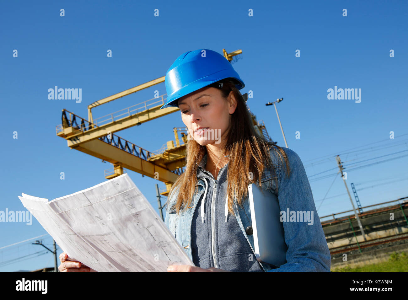 Woman engineer reading construction plan on site Stock Photo - Alamy