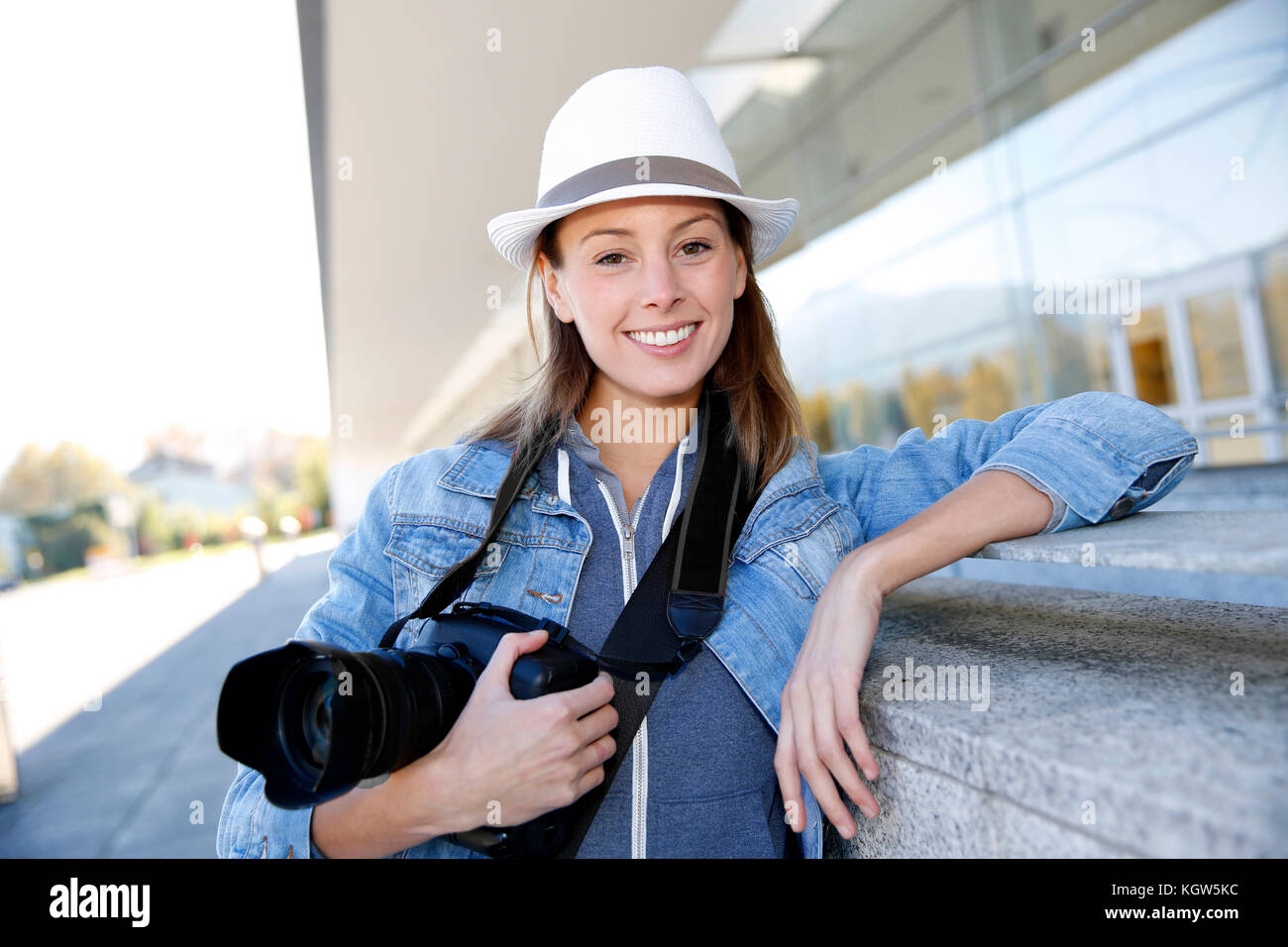 Smiling reporter standing outside with photo camera Stock Photo - Alamy