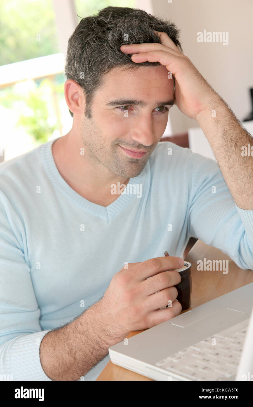 Man at home connected on internet with laptop Stock Photo - Alamy