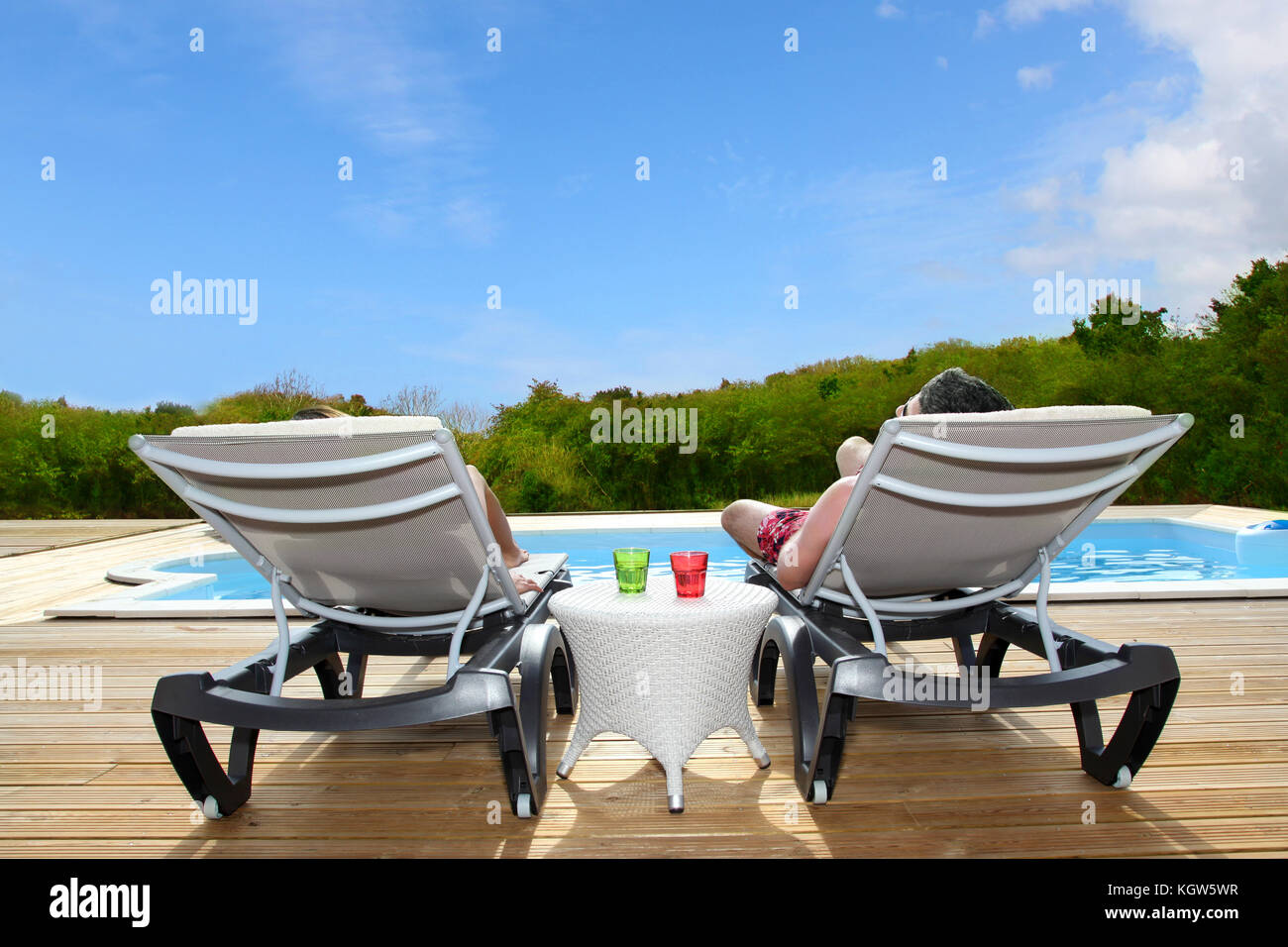 Back view of people relaxing on pool deck chairs Stock Photo - Alamy