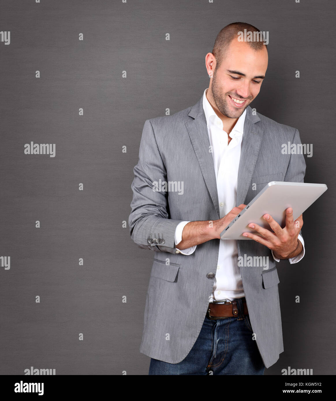 Cool businessman using touchpad on grey background Stock Photo - Alamy