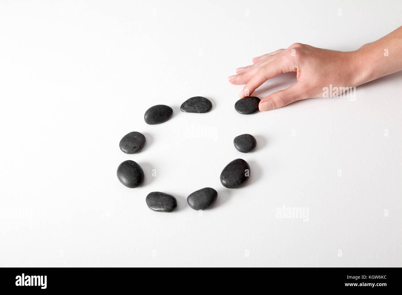 Human hand arranging line of pebbles in circle Stock Photo - Alamy