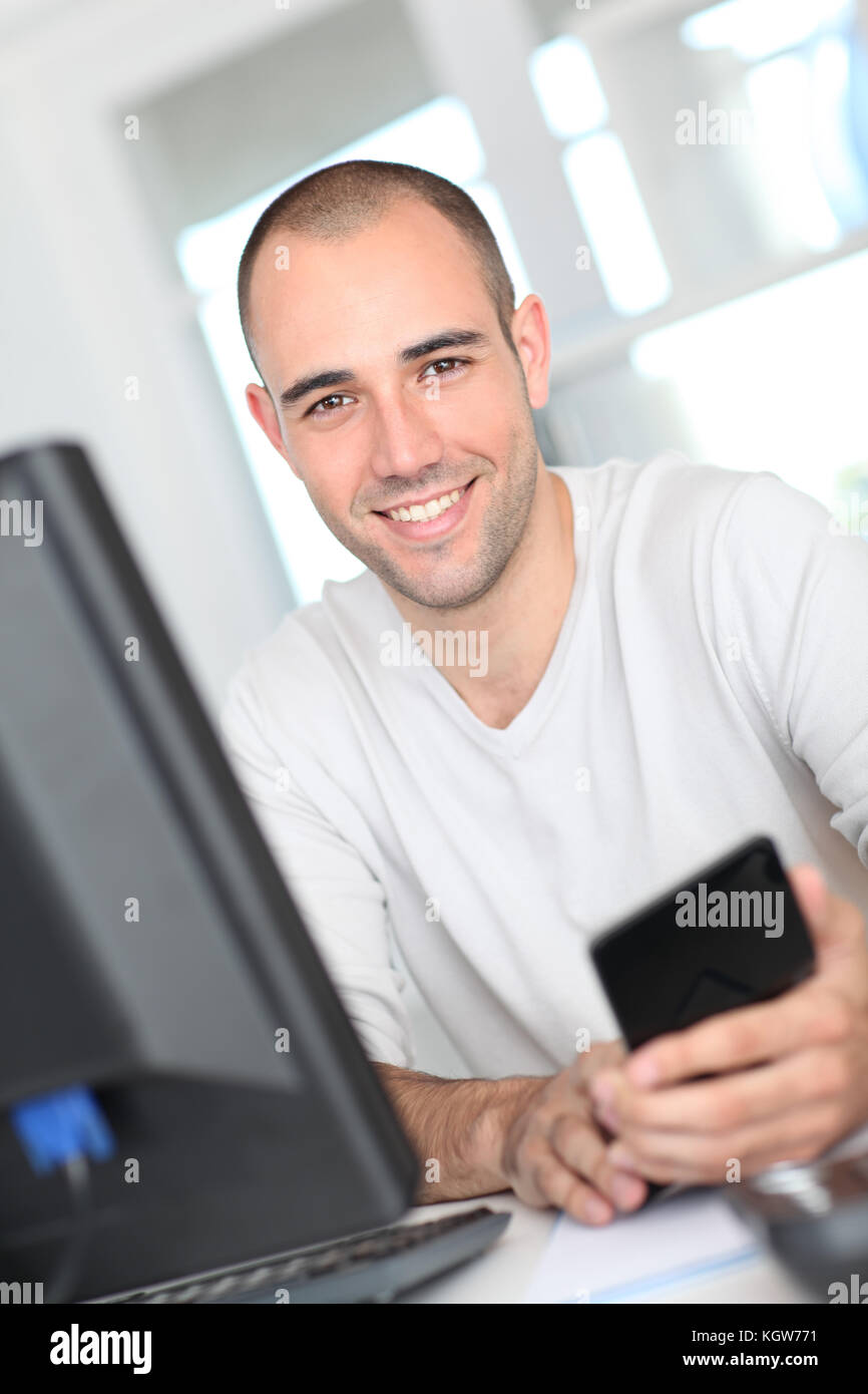 Smiling office worker sitting in front of desktop computer Stock Photo ...