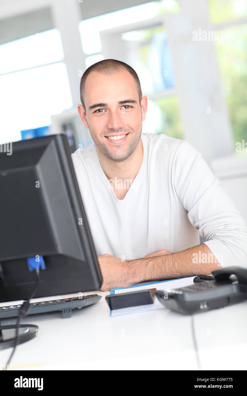 Smiling office worker sitting in front of desktop computer Stock Photo ...