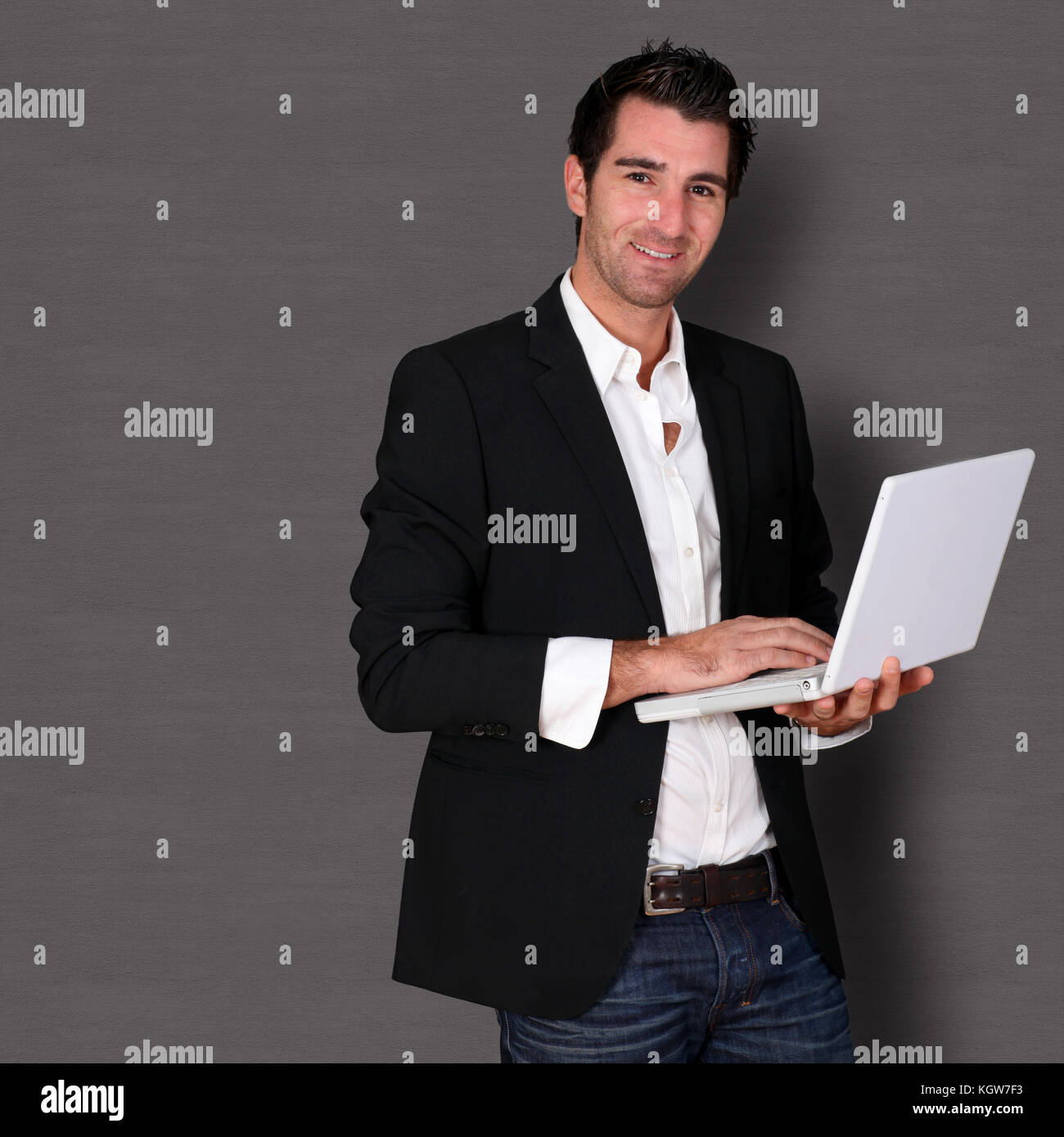 Man standing on dark background with laptop Stock Photo - Alamy