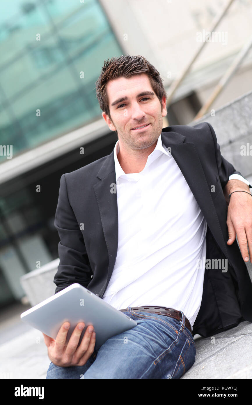 Man using electronic tablet in front of modern building Stock Photo - Alamy