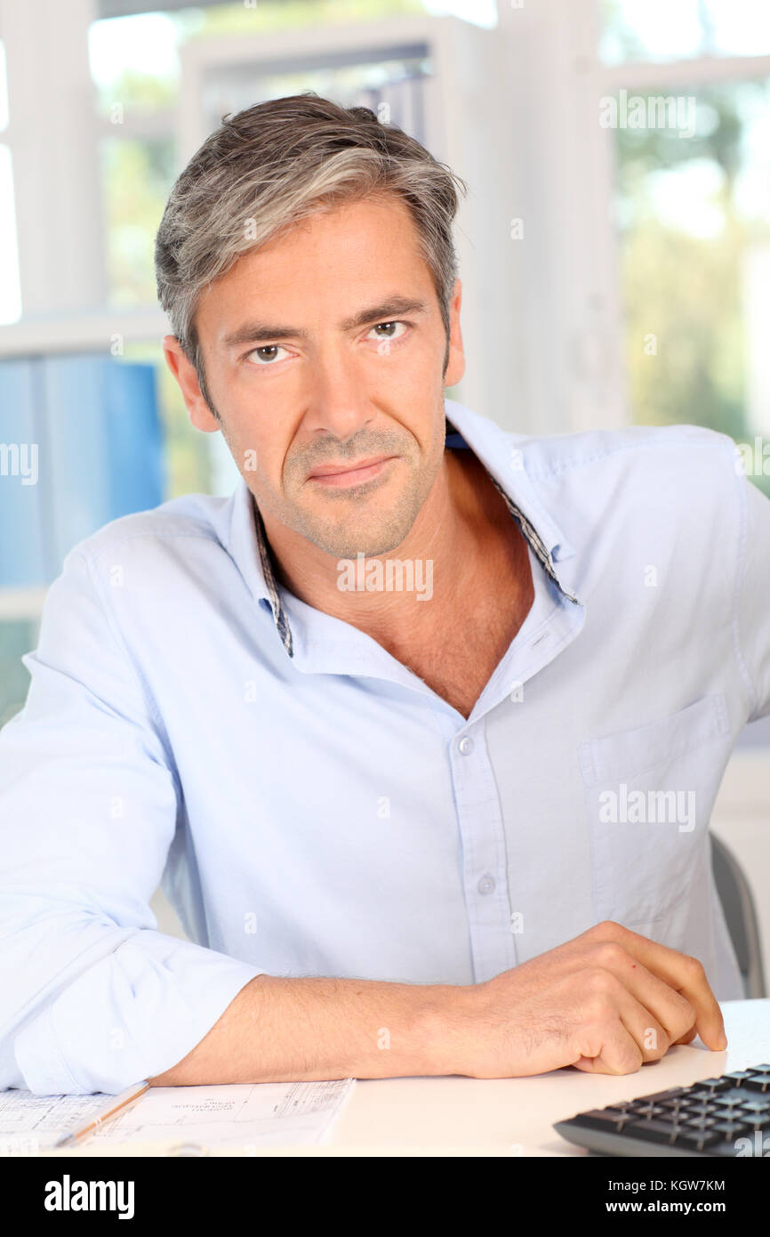 Handsome man sitting at his desk in office Stock Photo - Alamy