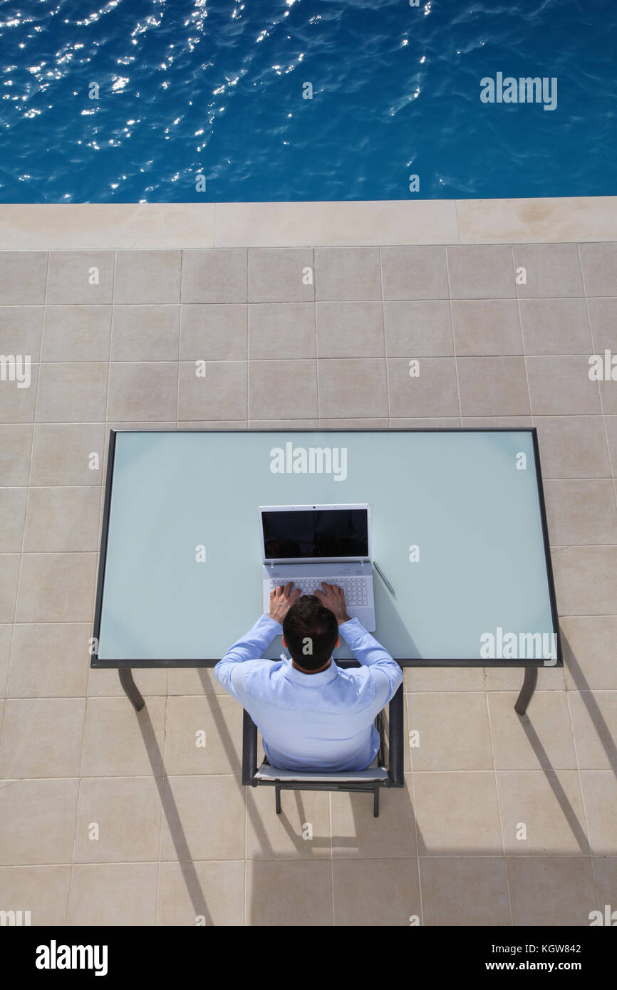 View from above of man using computer by swimming-pool Stock Photo - Alamy
