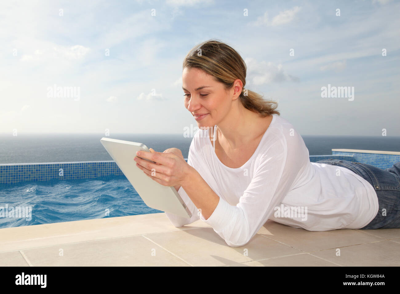 Woman using electronic tablet by swimming pool Stock Photo - Alamy
