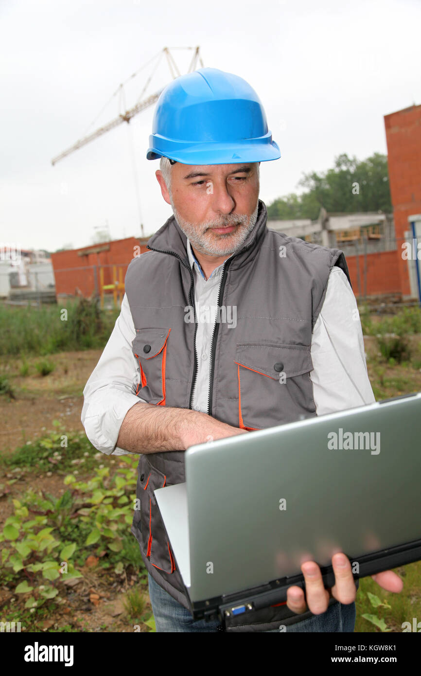 Site manager with laptop computer checking construction Stock Photo - Alamy