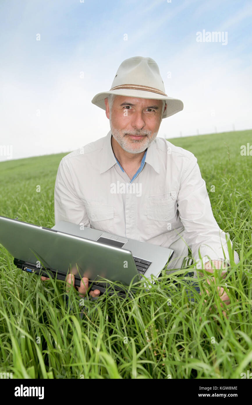 Farmer examining crop with laptop computer Stock Photo - Alamy
