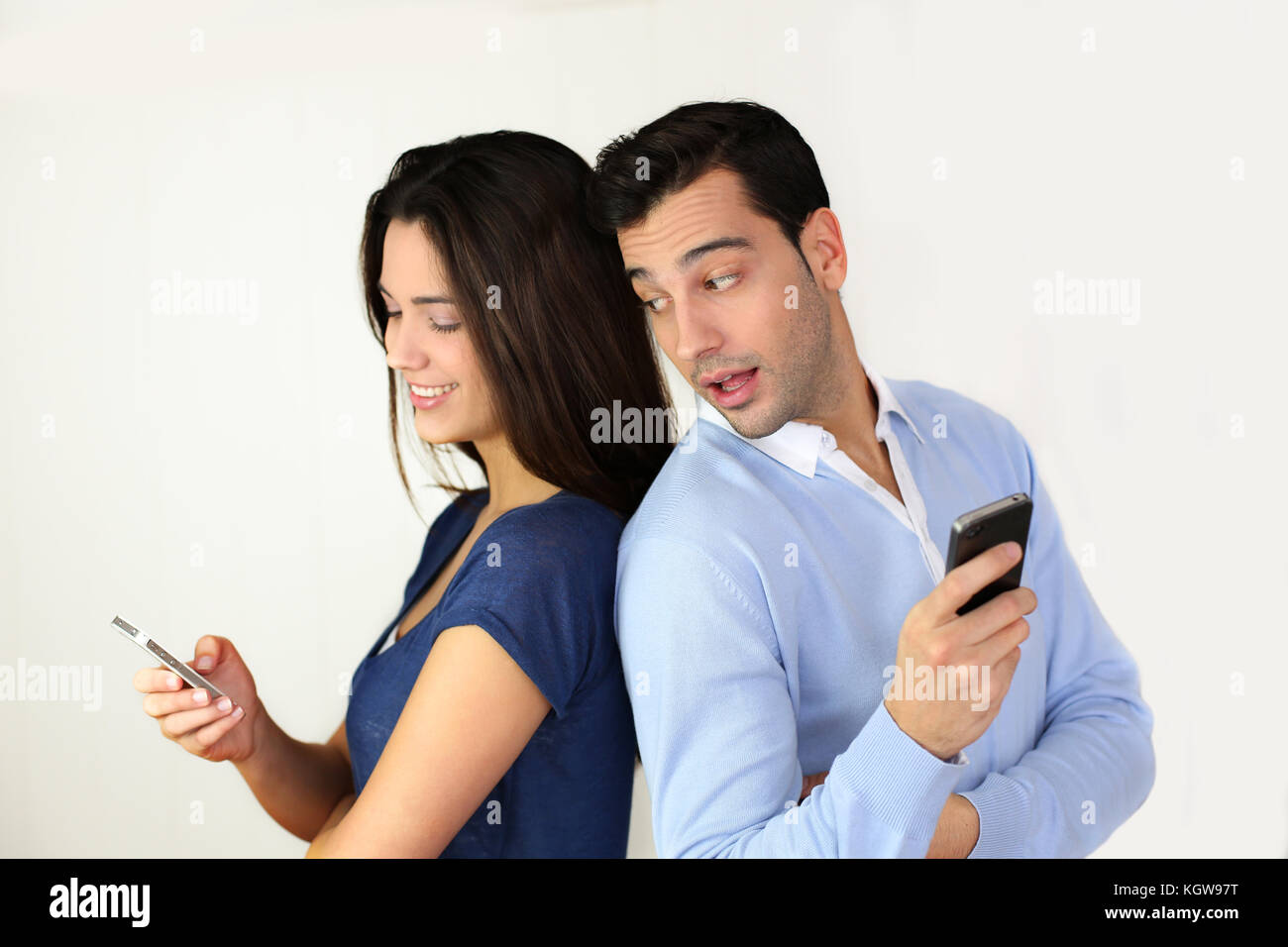 Couple standing back to back and using smartphone Stock Photo - Alamy