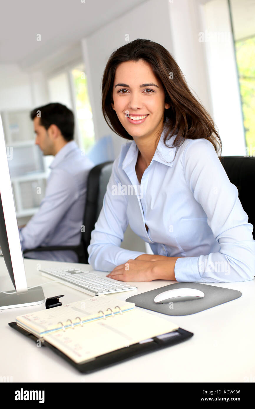 Smiling office worker in front of desktop computer Stock Photo - Alamy