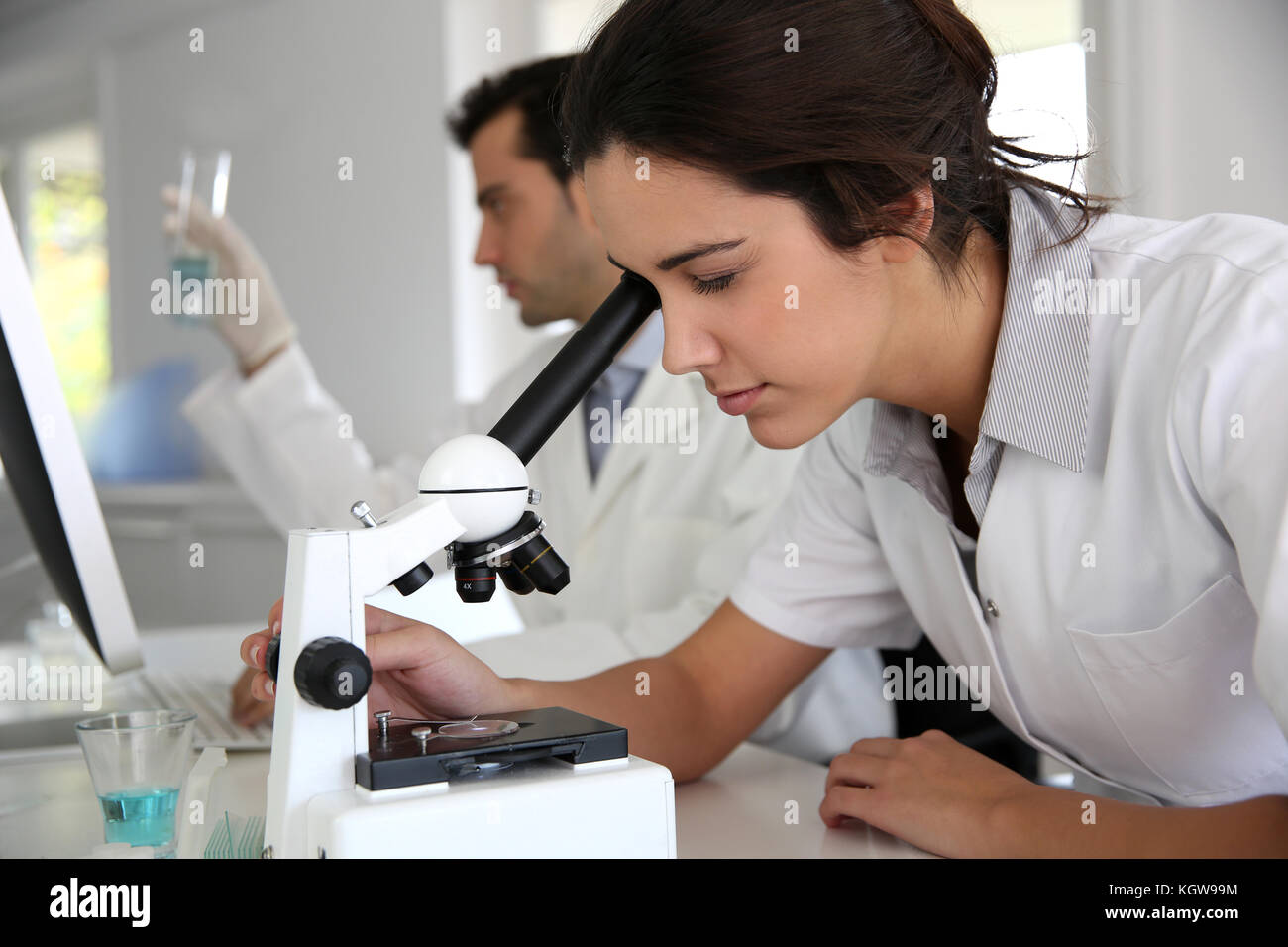Young woman looking through microscope lense Stock Photo - Alamy