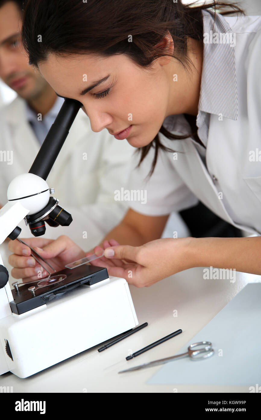 Young woman looking through microscope lense Stock Photo - Alamy