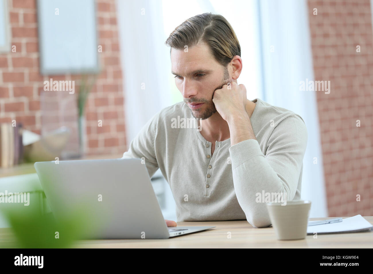 Blond guy sitting in front of laptop computer at home Stock Photo - Alamy