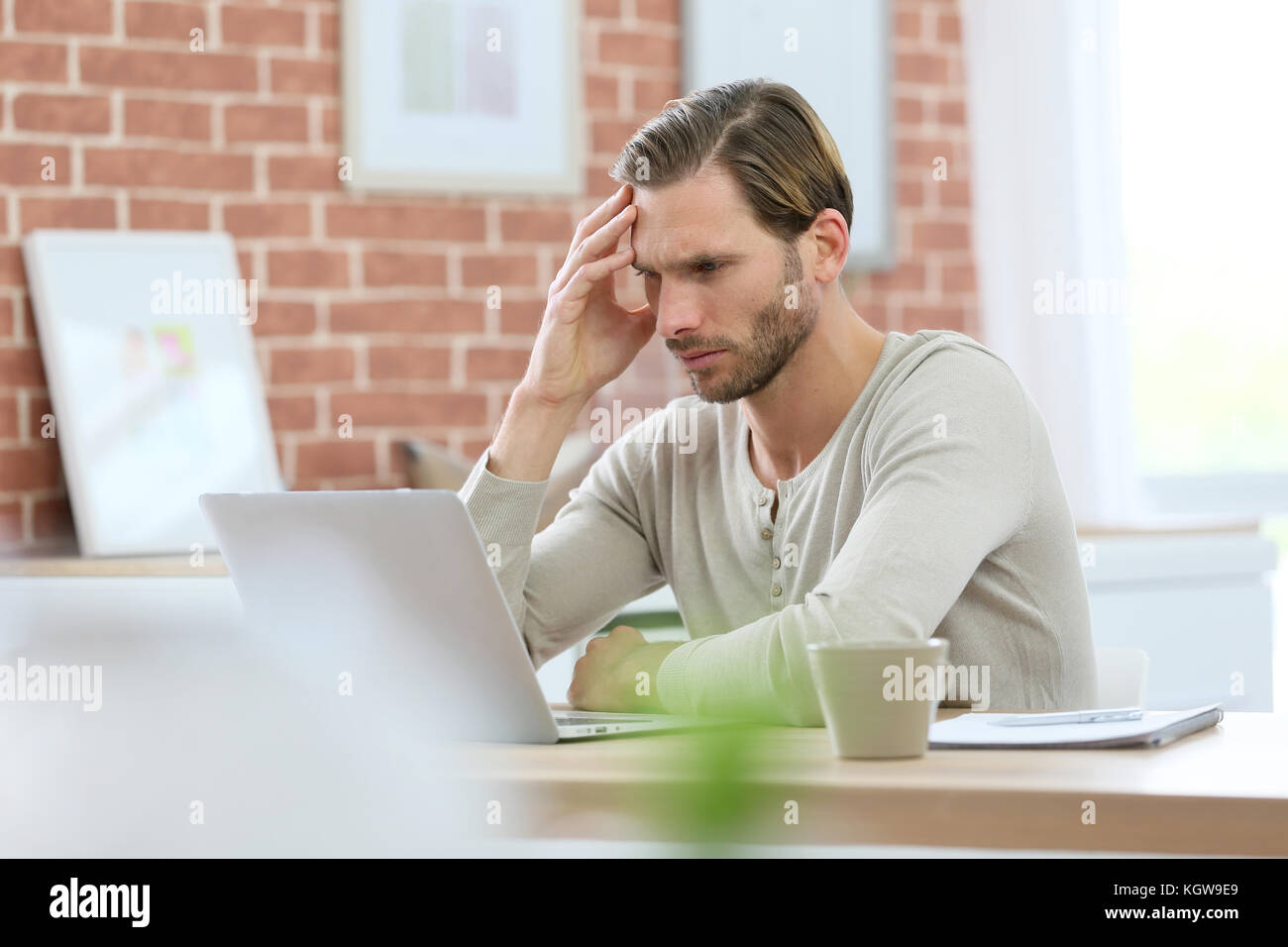 Blond guy sitting in front of laptop computer at home Stock Photo - Alamy