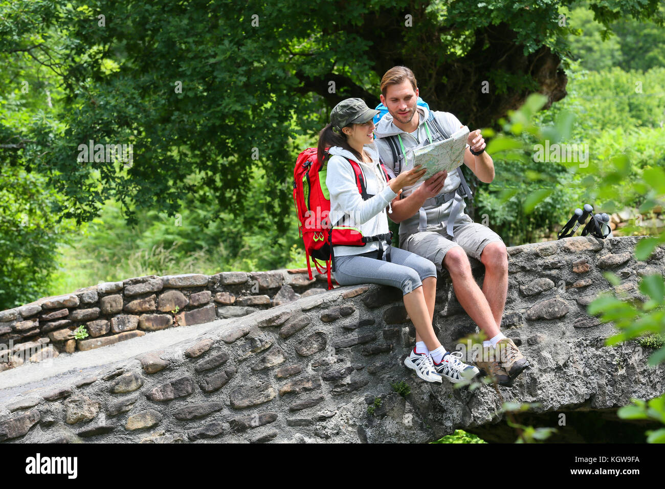 Couple of hikers reading map on stone bridge Stock Photo - Alamy