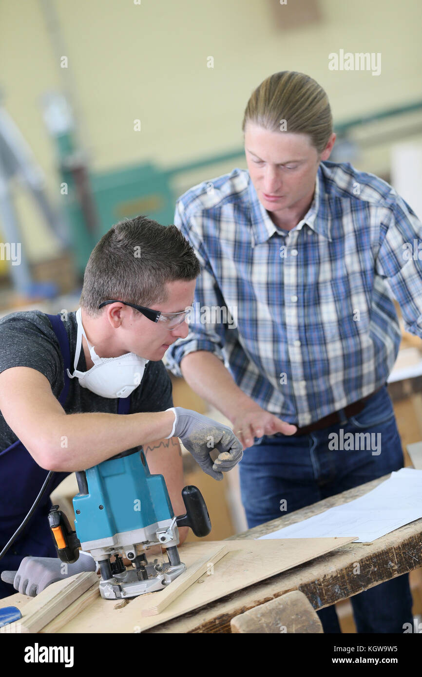 Apprentice with adult in carpentry school working on wood Stock Photo ...