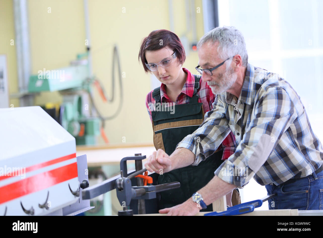 Carpenter showing apprentice how to use sawing machine Stock Photo - Alamy