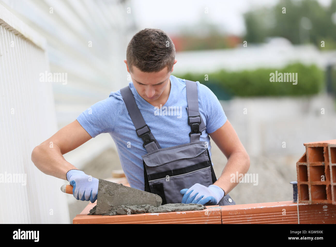 Young brick layer working outside on brick wall construction Stock ...