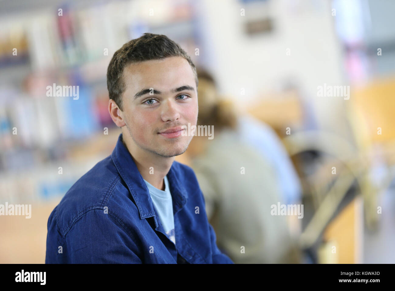 Student boy sitting on table in library room Stock Photo - Alamy